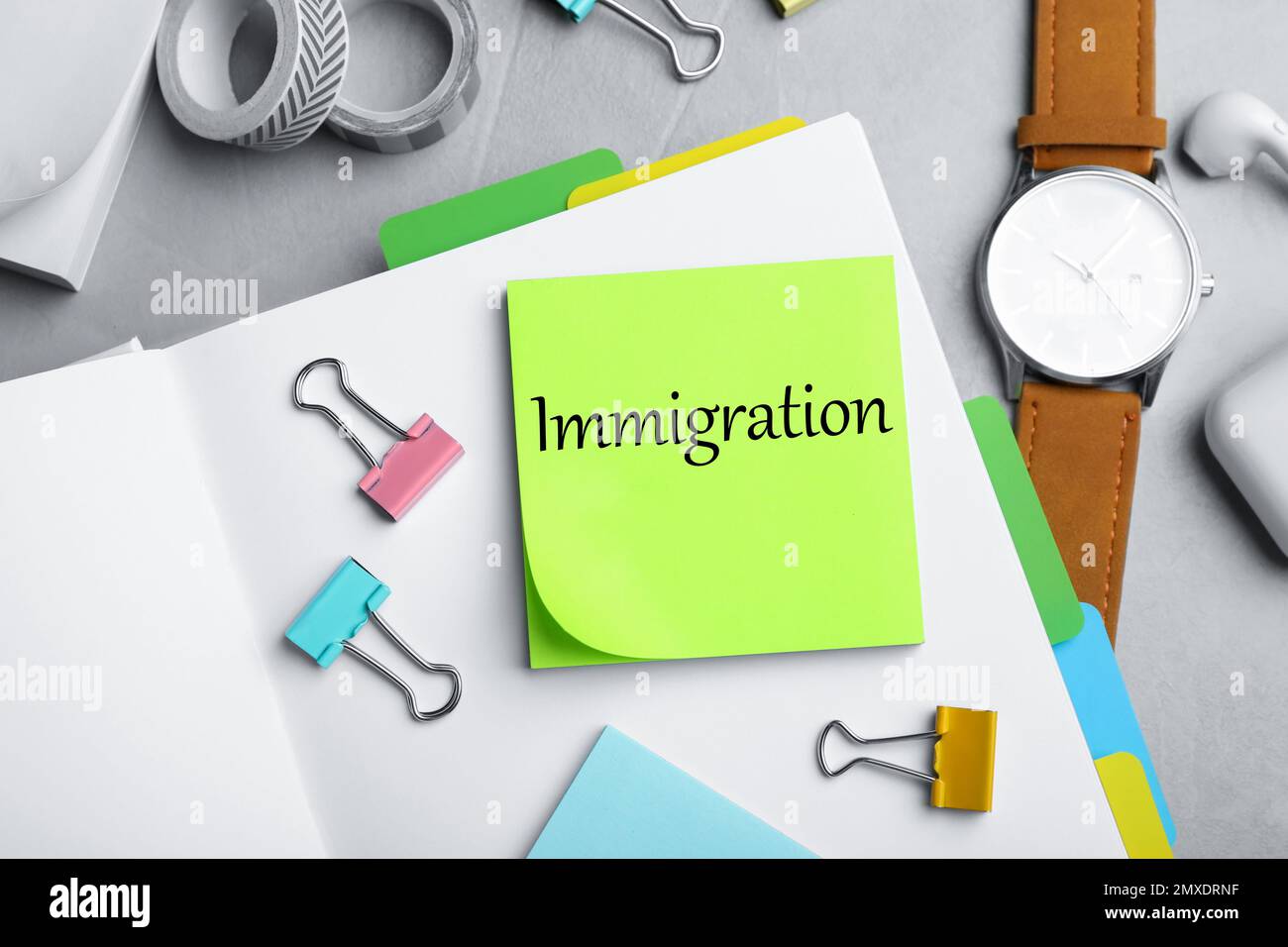 Note with word IMMIGRATION and stationery on grey grey table, flat lay ...