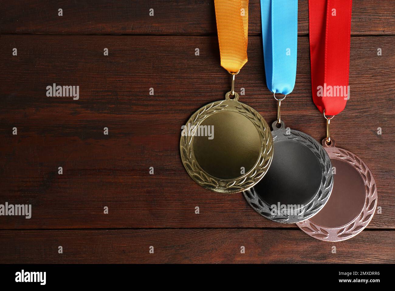 Gold, silver and bronze medals on wooden background, flat lay. Space ...