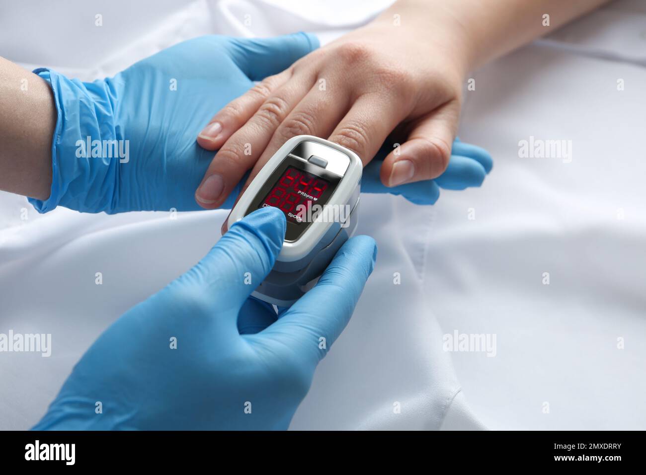Doctor examining patient with modern fingertip pulse oximeter in bed ...
