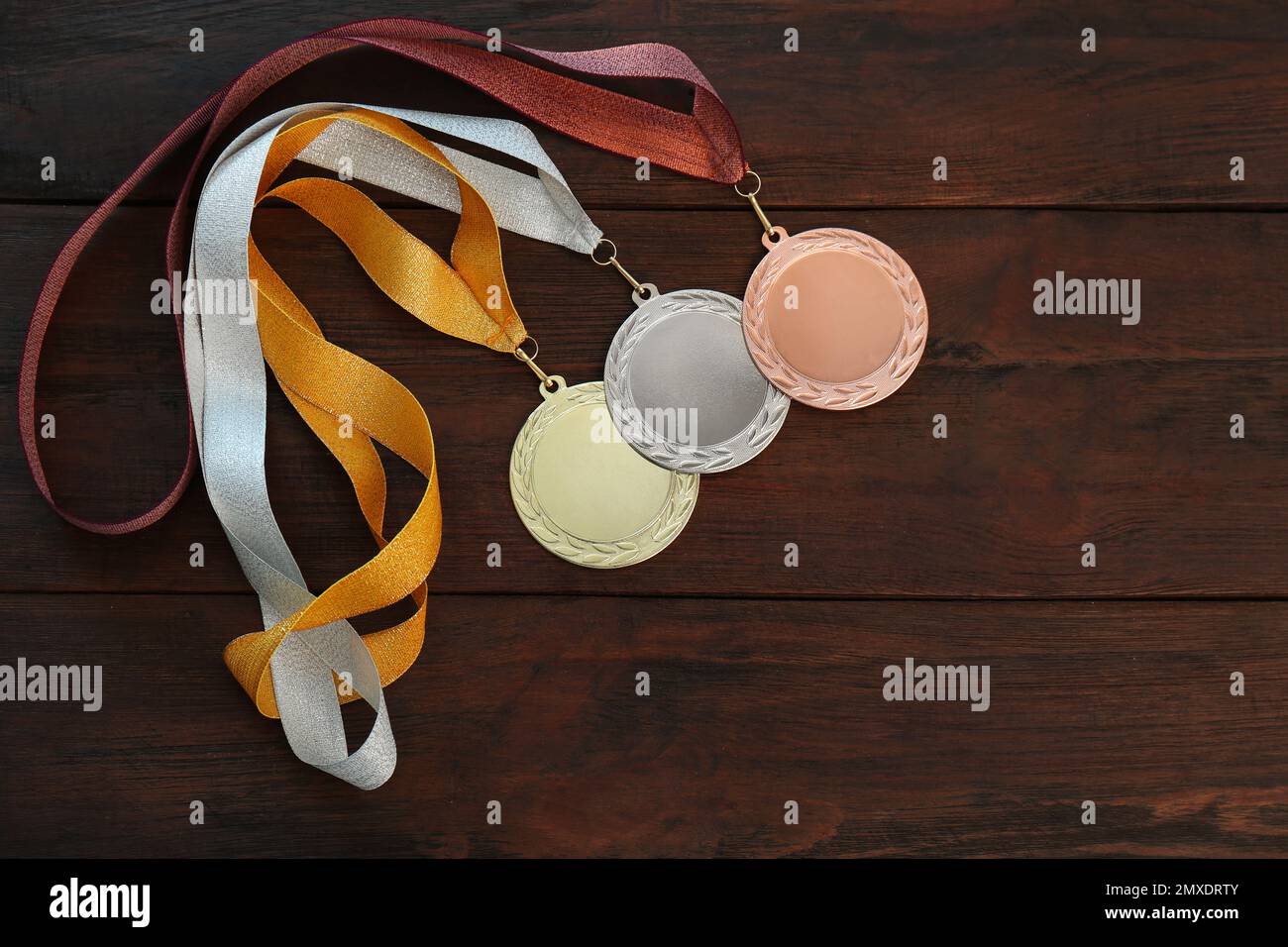 Gold, silver and bronze medals on wooden background, flat lay. Space ...