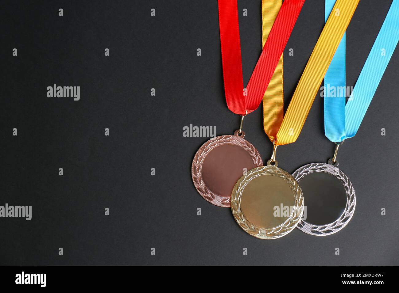 Gold, silver and bronze medals on black background, flat lay. Space for ...