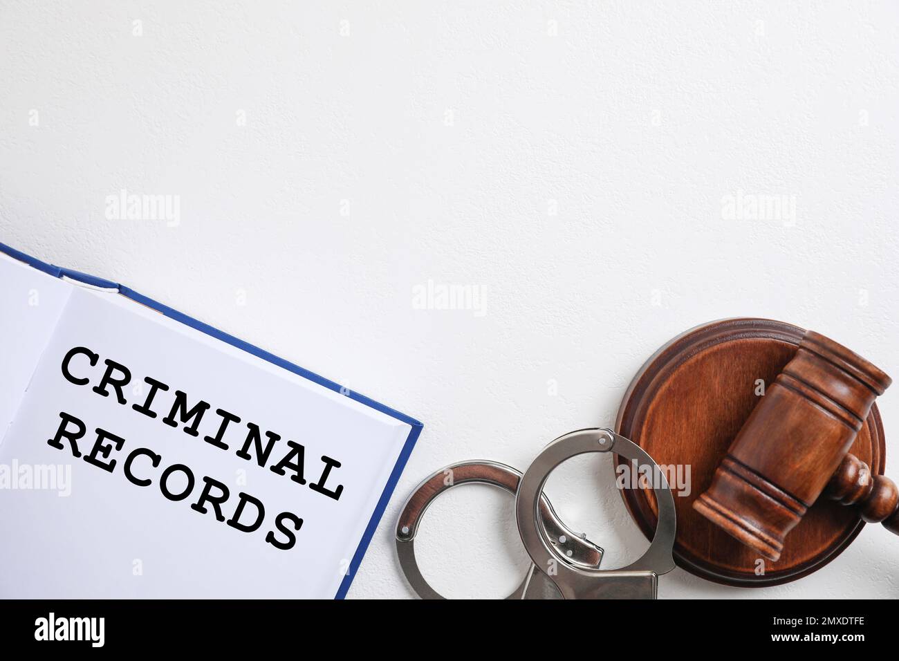 Book with words CRIMINAL RECORDS, handcuffs and gavel on white ...