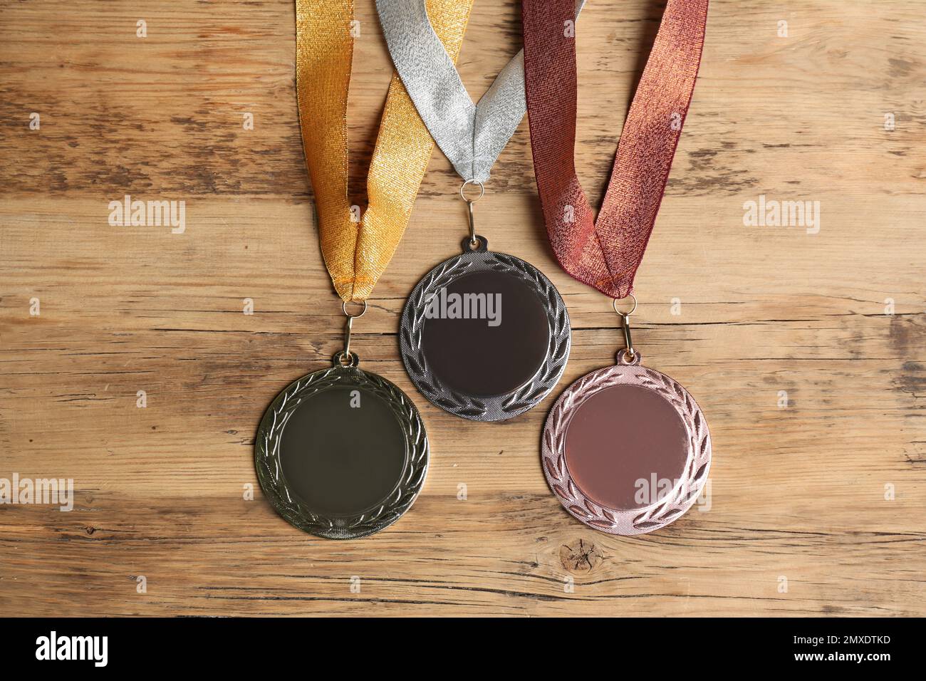 Gold, silver and bronze medals on wooden background, flat lay. Space ...
