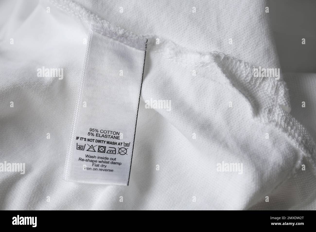 Clothing label with care symbols and material content on white shirt ...