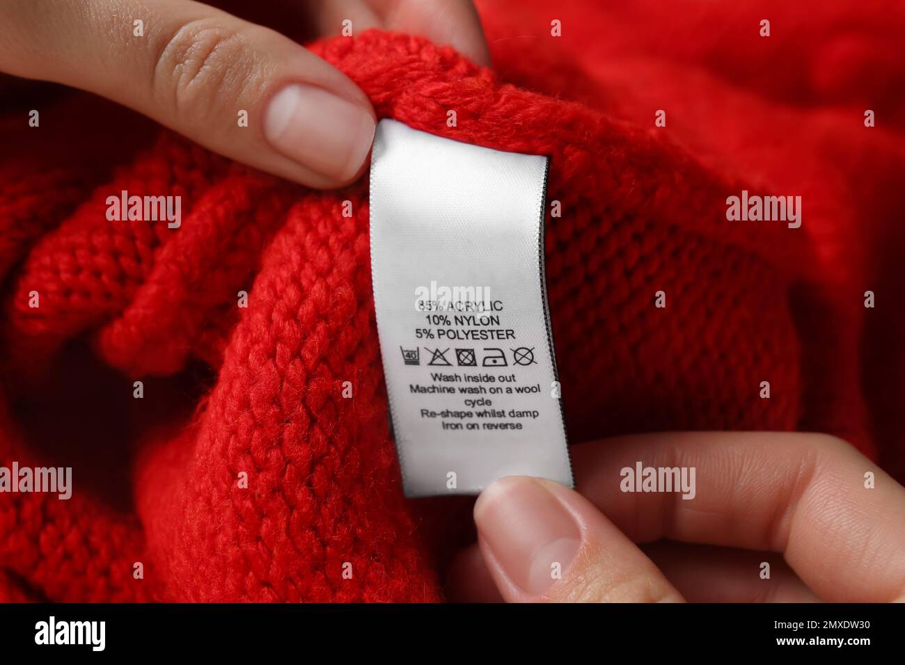 Woman reading clothing label with care symbols and material content on ...