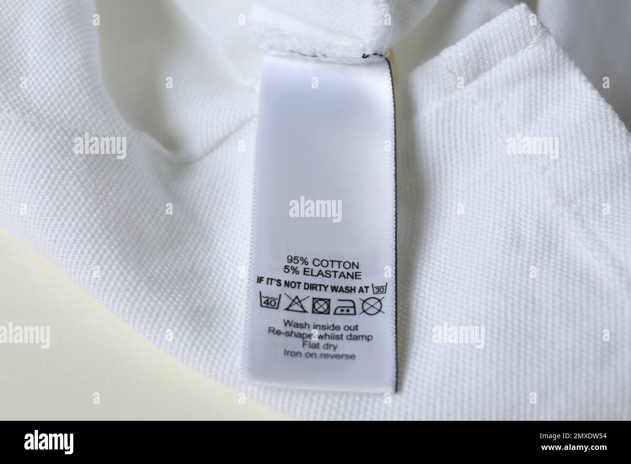 Clothing label with care symbols and material content on white shirt ...
