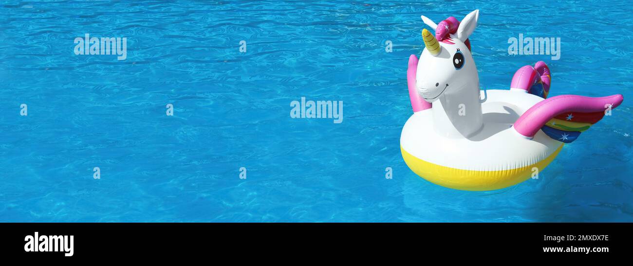 Funny inflatable unicorn ring floating in swimming pool on sunny day ...