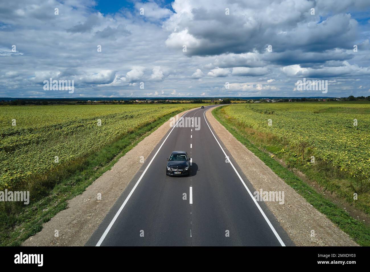 Aerial view of intercity road between green agricultural fields with ...