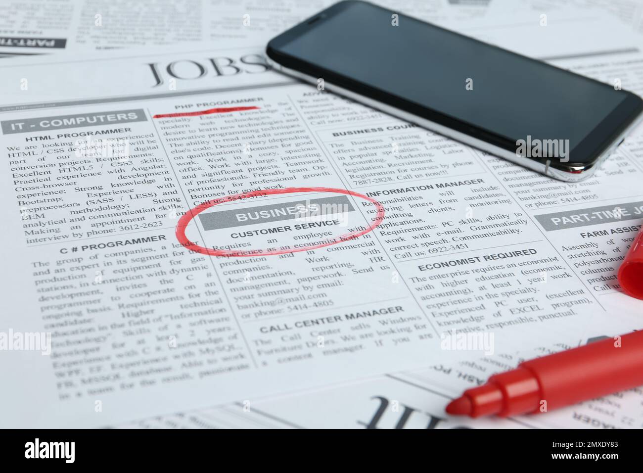 Newspaper with marked advertisement and smartphone. Job search concept ...
