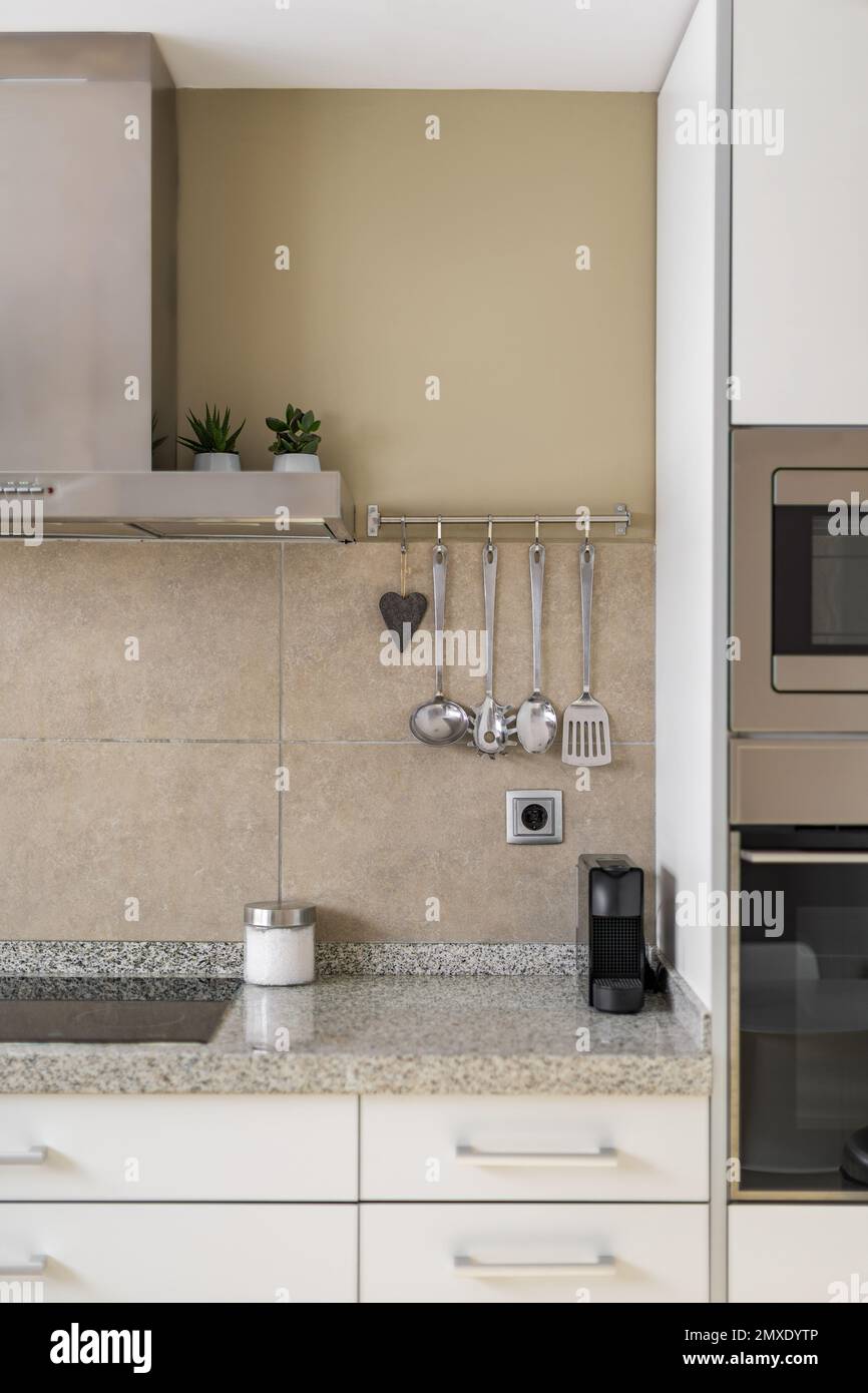 Part of kitchen with marble countertop, wall with beige marble tiles ...