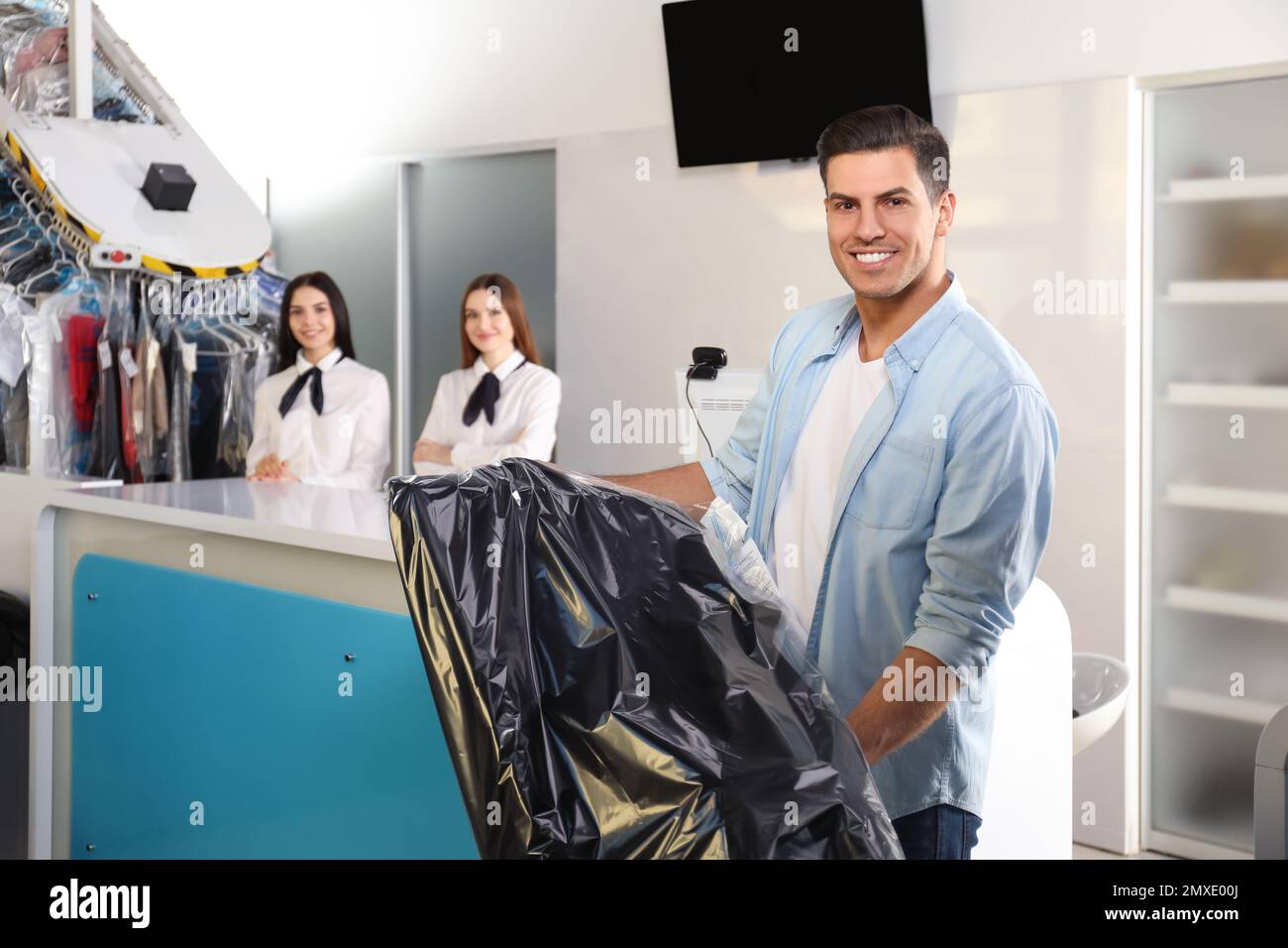 Happy client with clothes at modern dry-cleaner's Stock Photo - Alamy