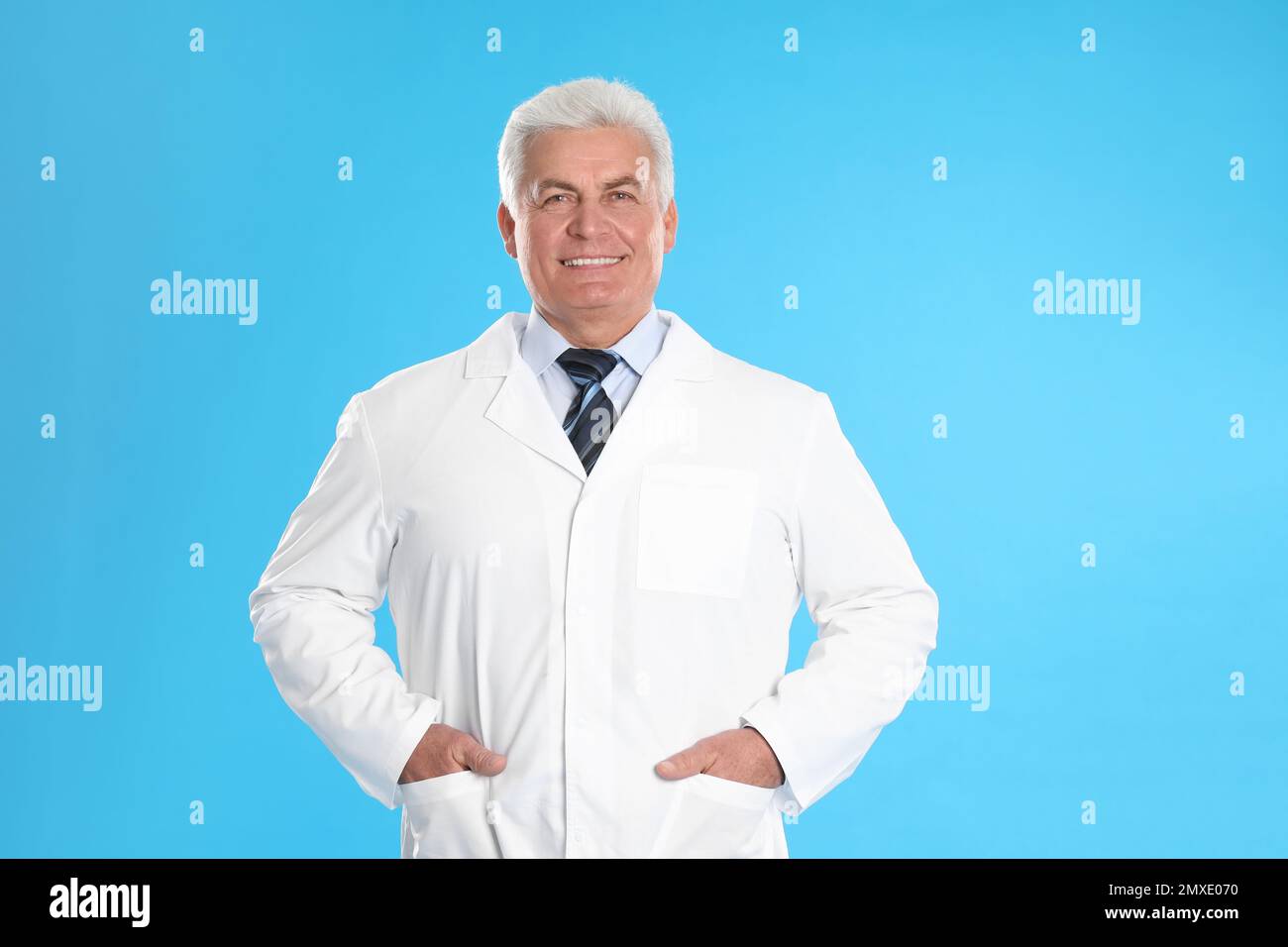 Happy senior man in lab coat on light blue background Stock Photo - Alamy