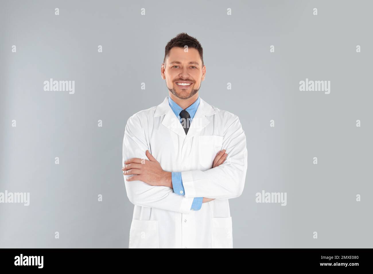 Happy man in lab coat on light grey background Stock Photo - Alamy