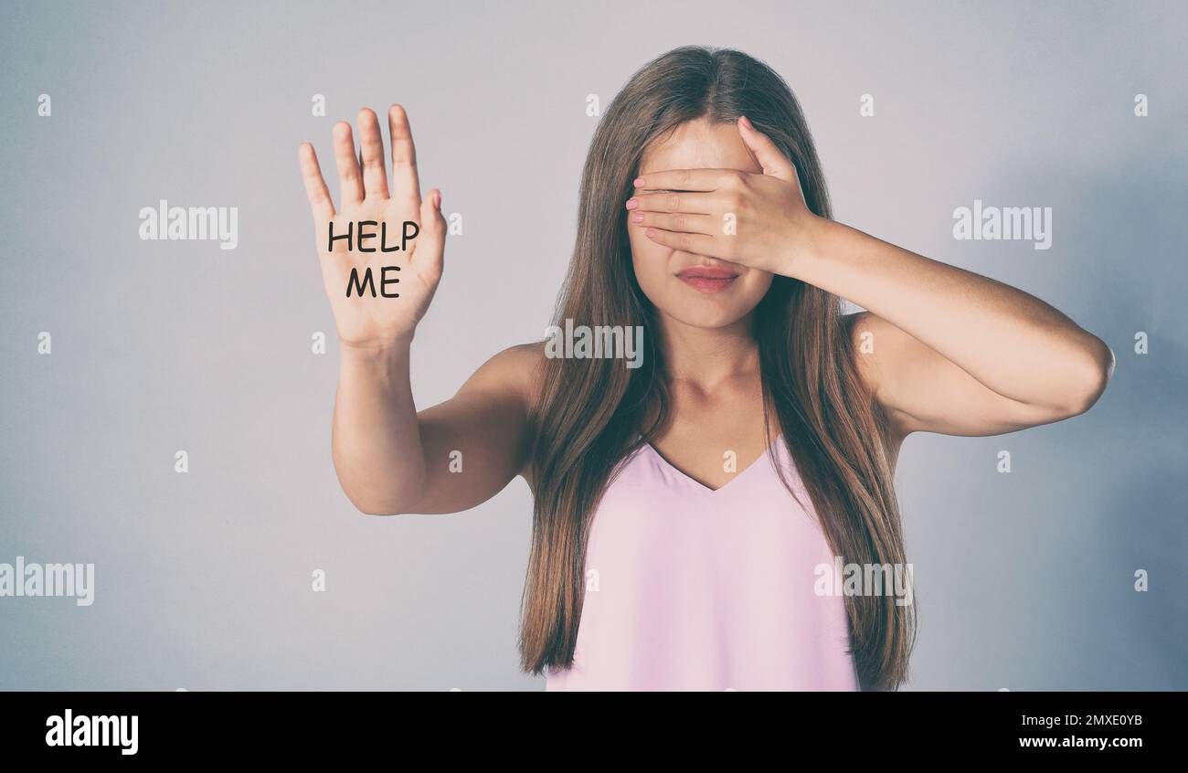 Young woman with text HELP ME on her hand near grey wall Stock Photo ...