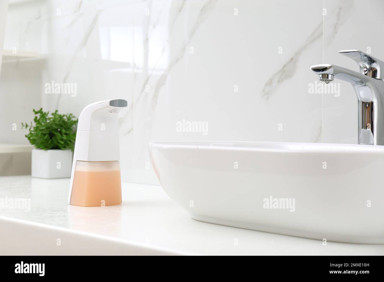 Modern automatic soap dispenser near sink in bathroom Stock Photo - Alamy