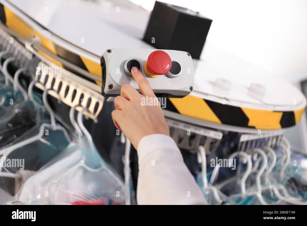 Worker pressing button on control panel of garment conveyor at modern ...