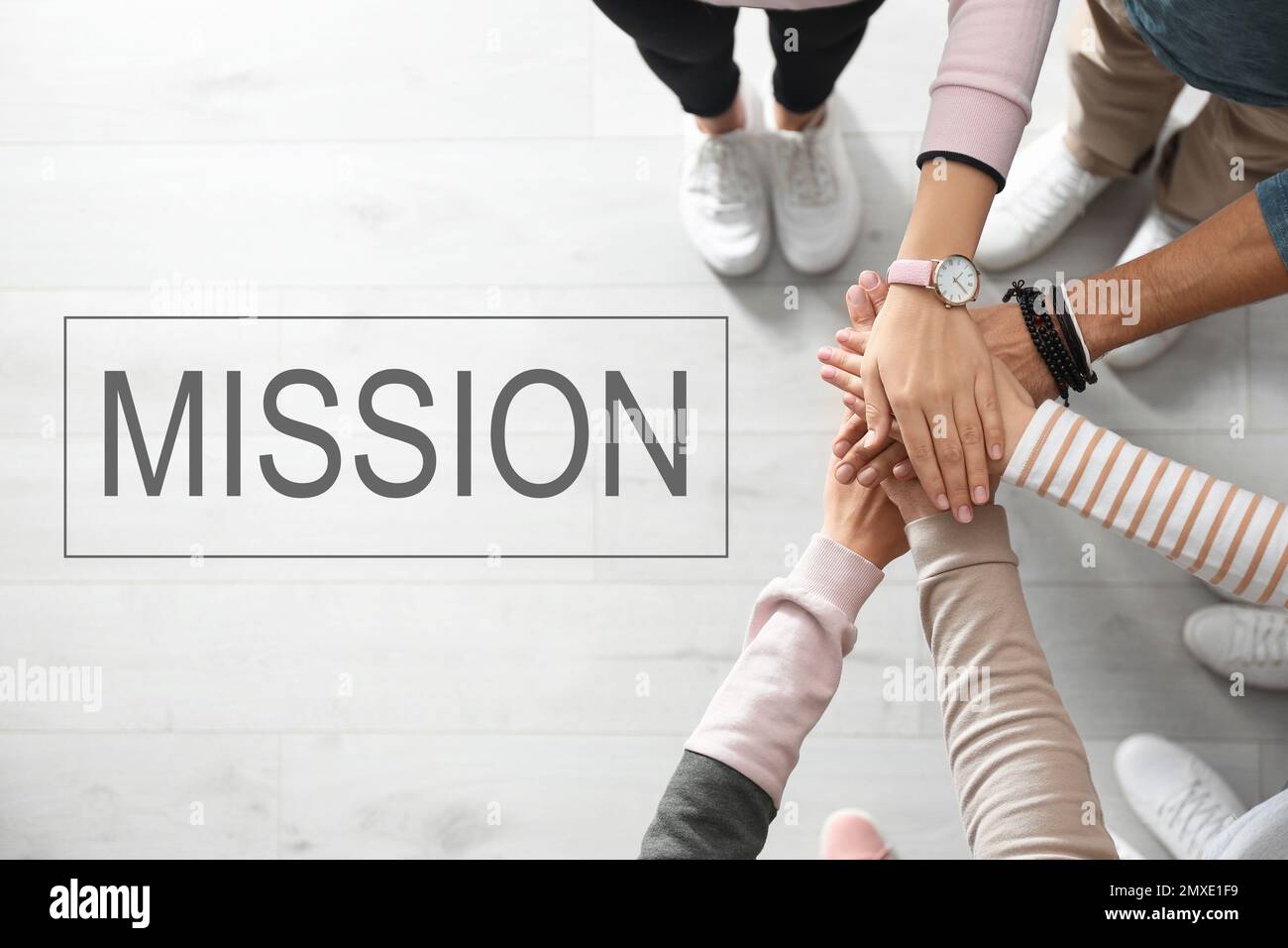 People holding hands together over light wooden background and text ...