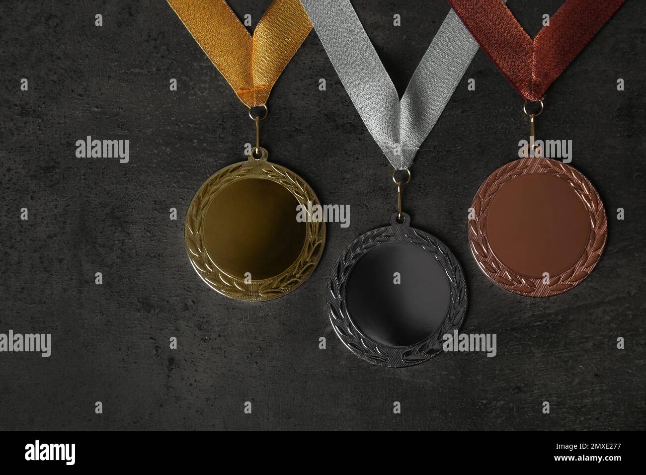 Gold, silver and bronze medals on grey stone background, flat lay ...