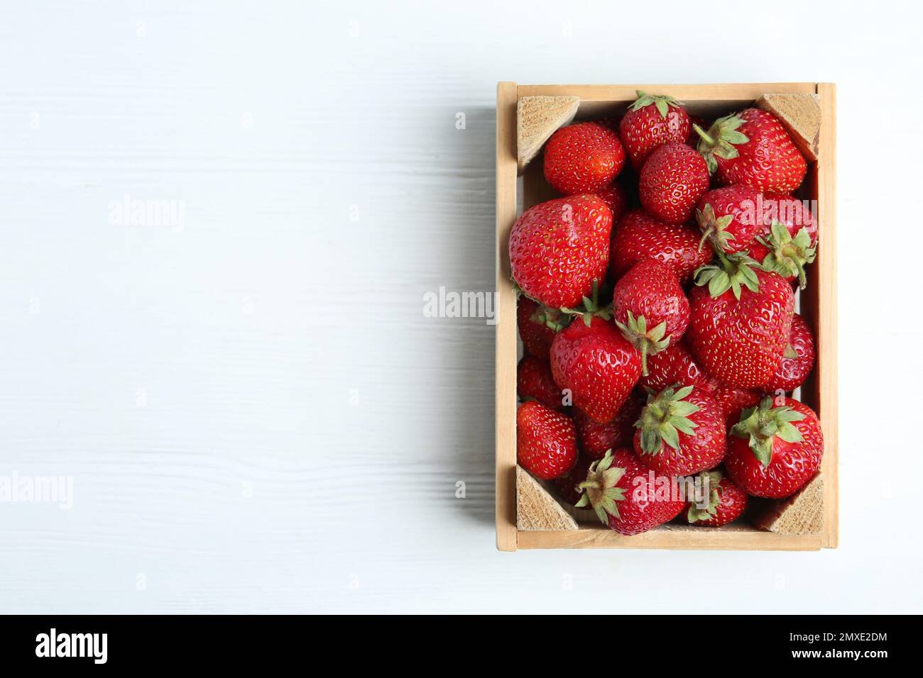 Delicious ripe strawberries in crate on white wooden table, top view ...