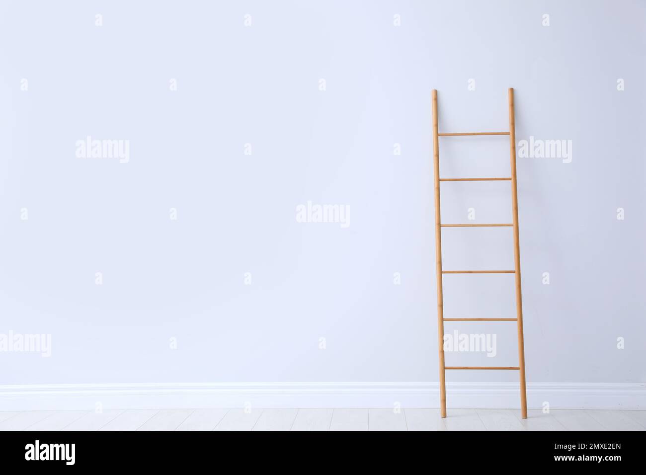 Modern wooden ladder near white wall. Space for text Stock Photo - Alamy
