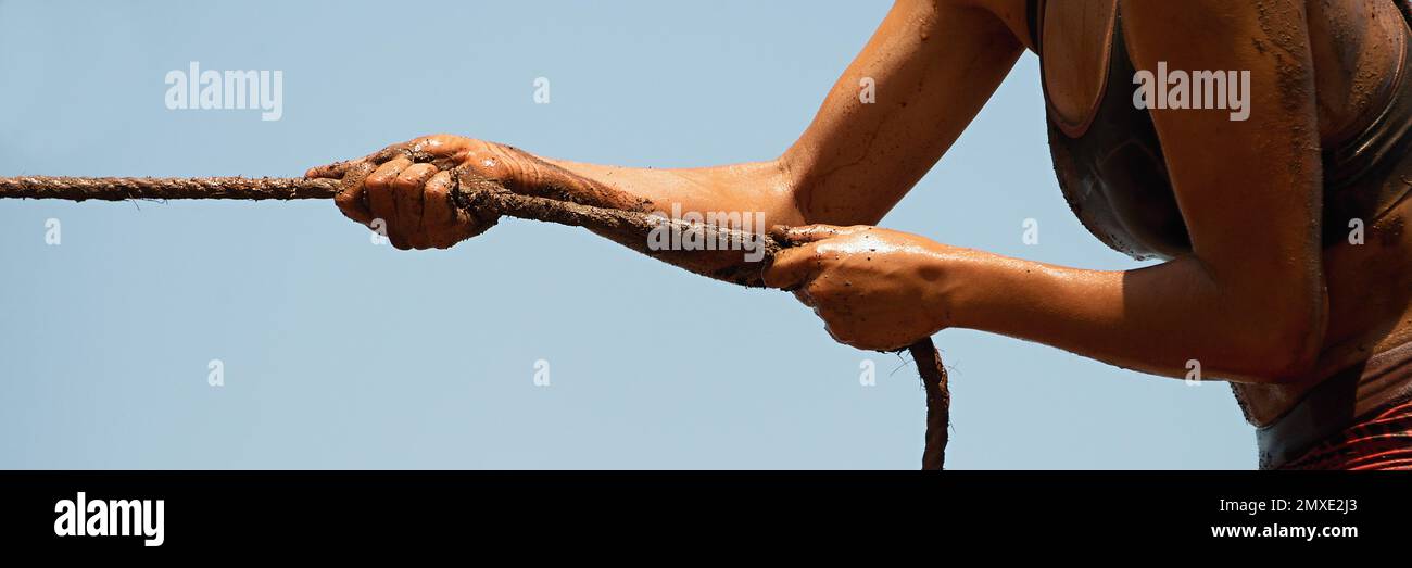Mud race runners,defeating obstacles by using ropes Stock Photo - Alamy