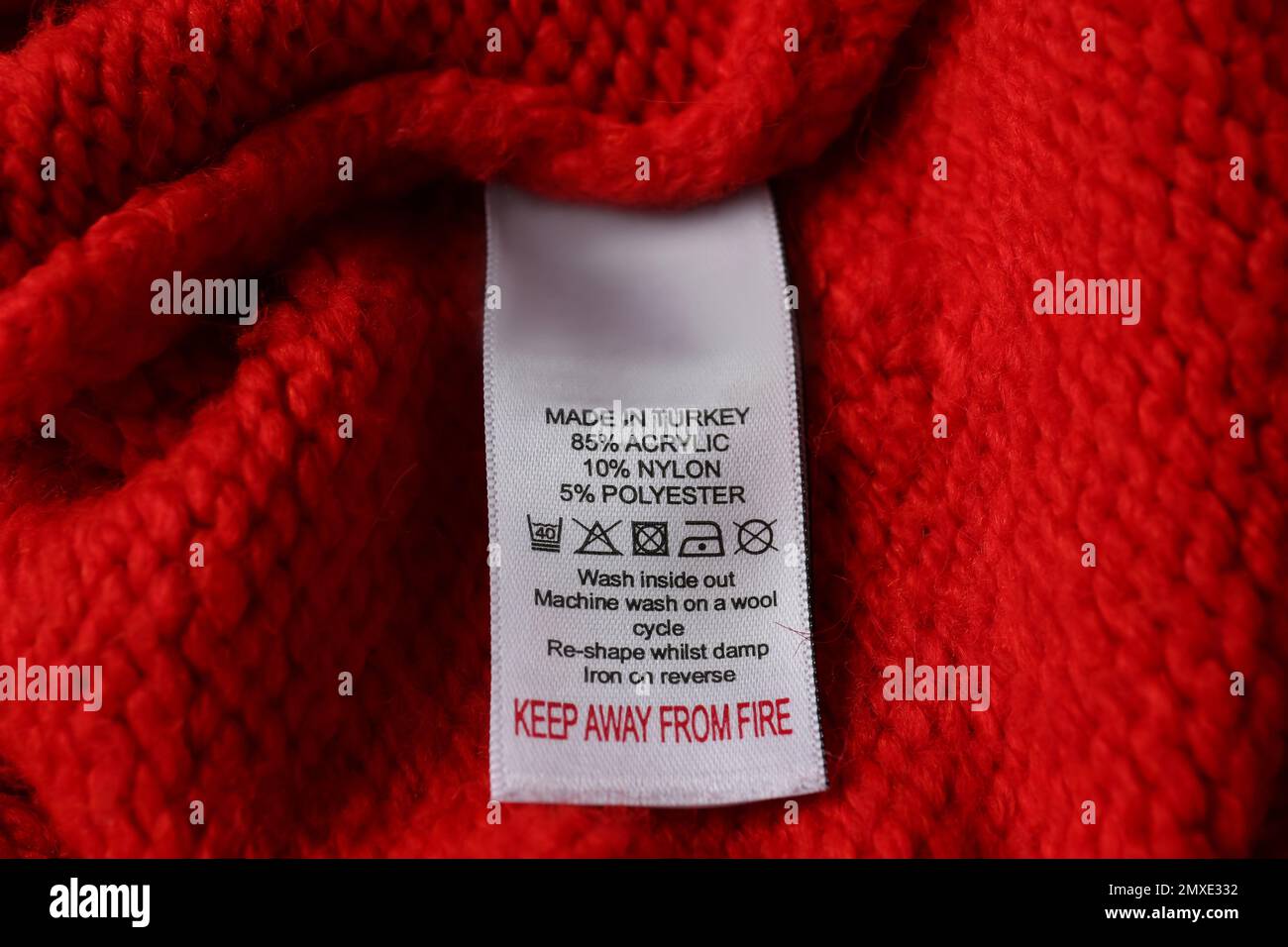 Clothing label with care symbols and material content on red sweater ...