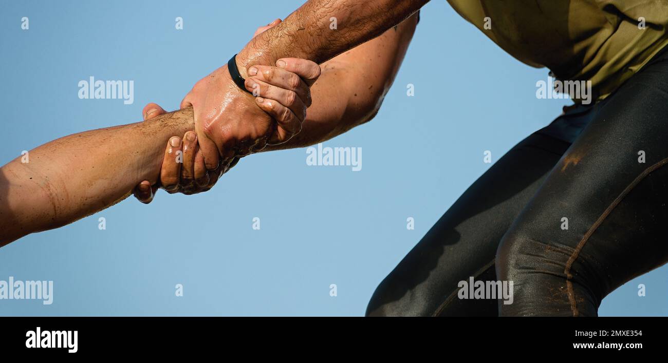 Mud race runners. Couple hold hands,help when overcoming hindrances mud ...