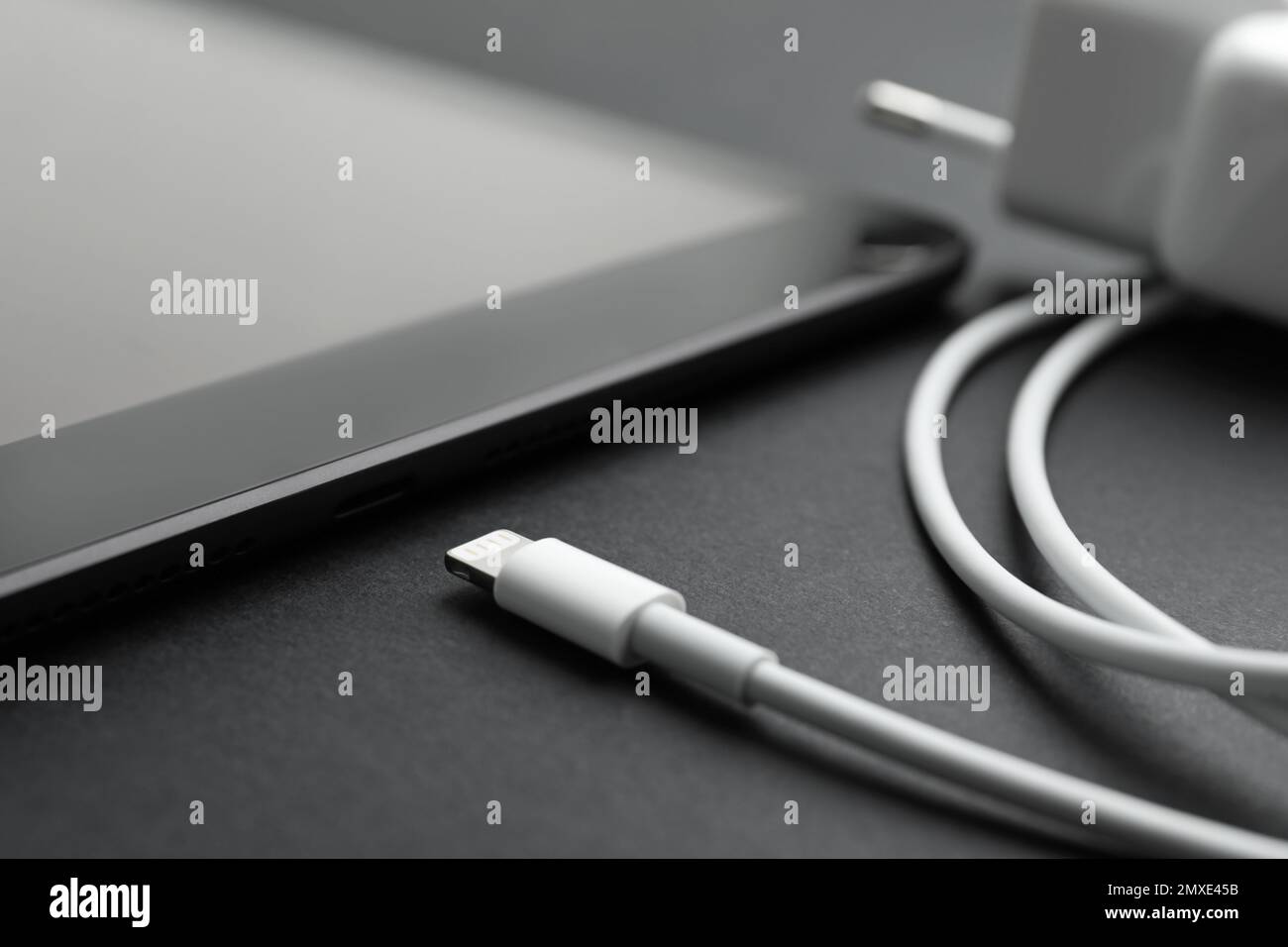Tablet and USB charge cable on black background, closeup. Modern ...