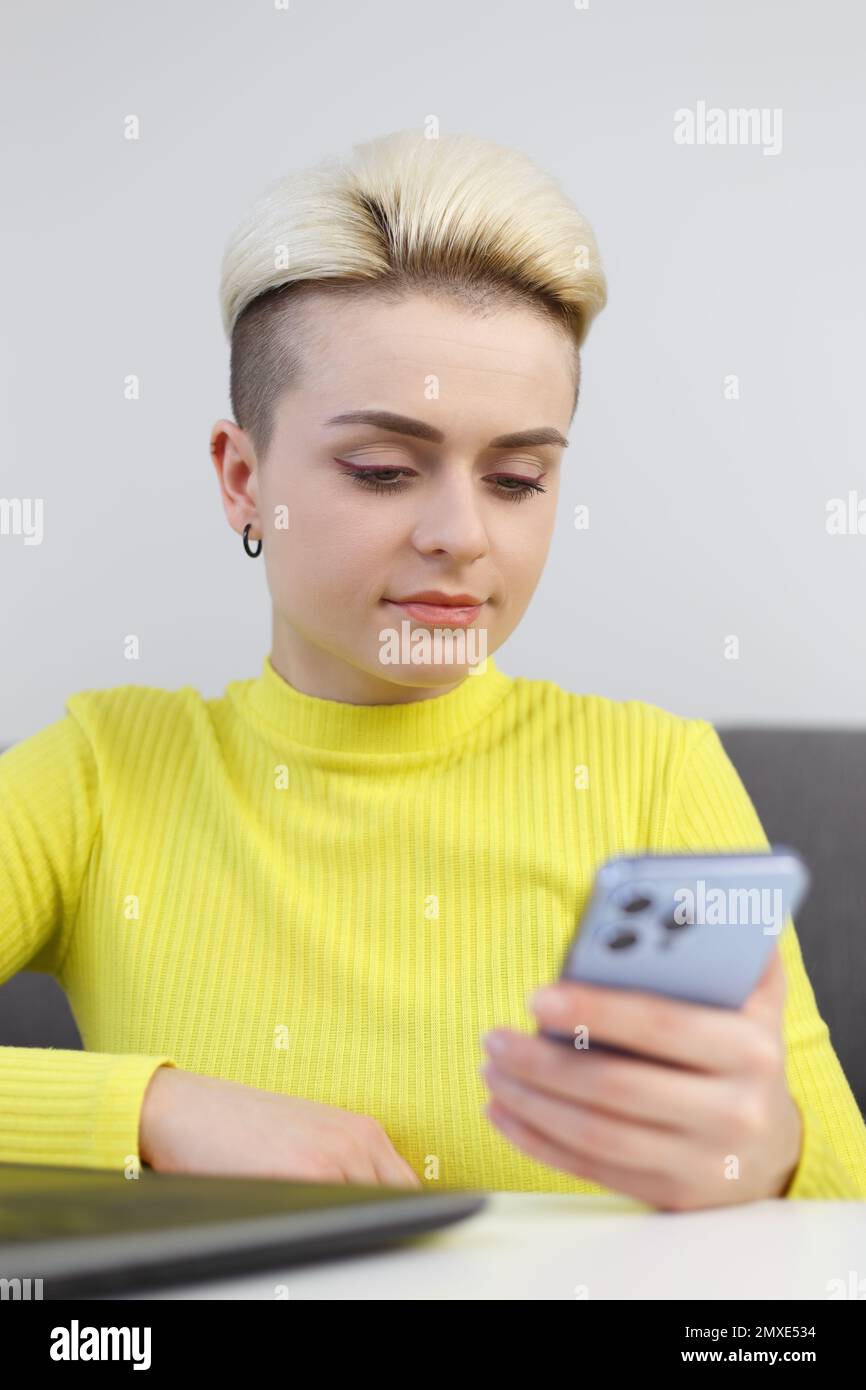 Beautiful young woman with short blonde hair using modern smart phone ...