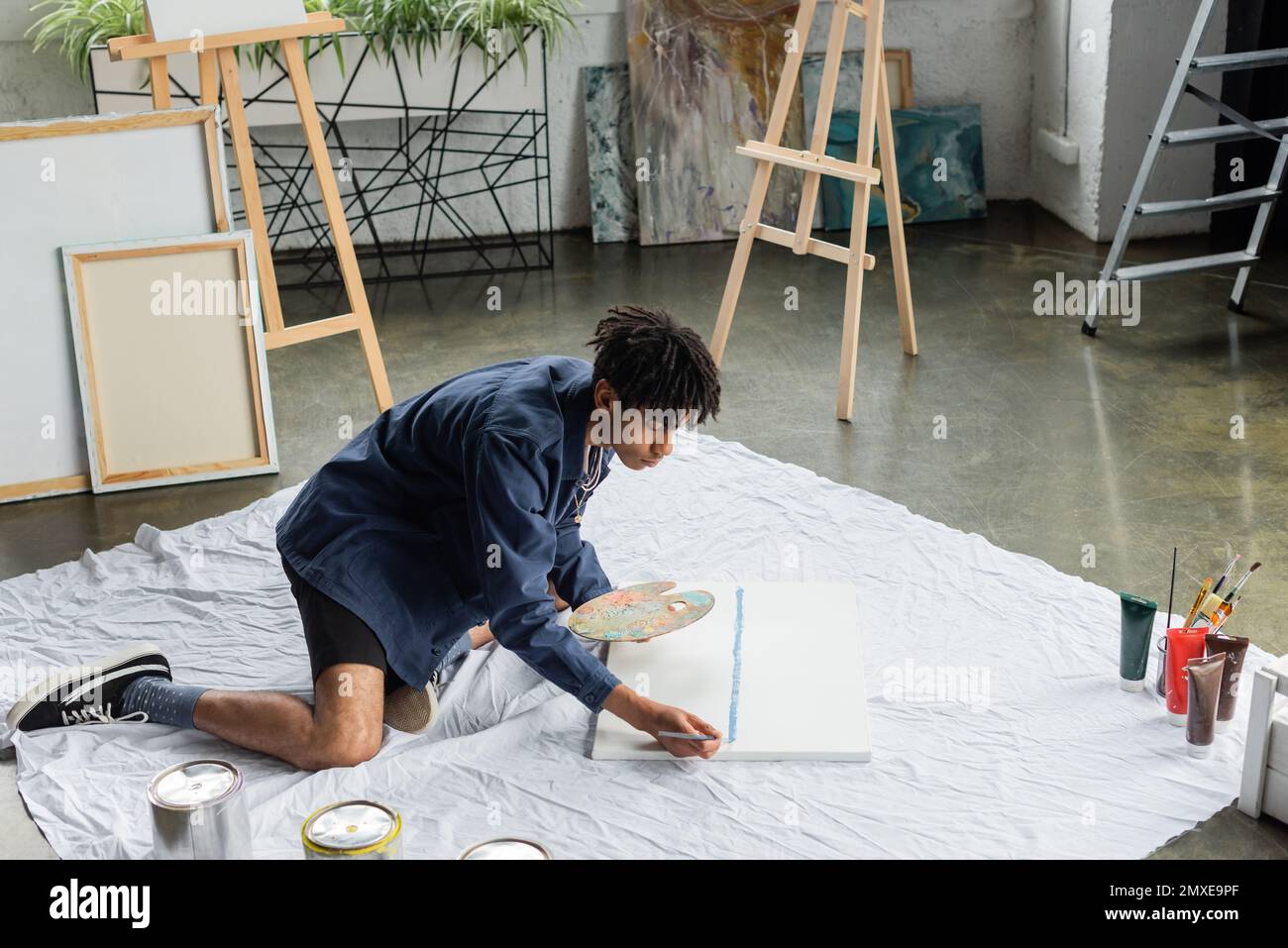 African american artist with palette painting on canvas in studio,stock ...