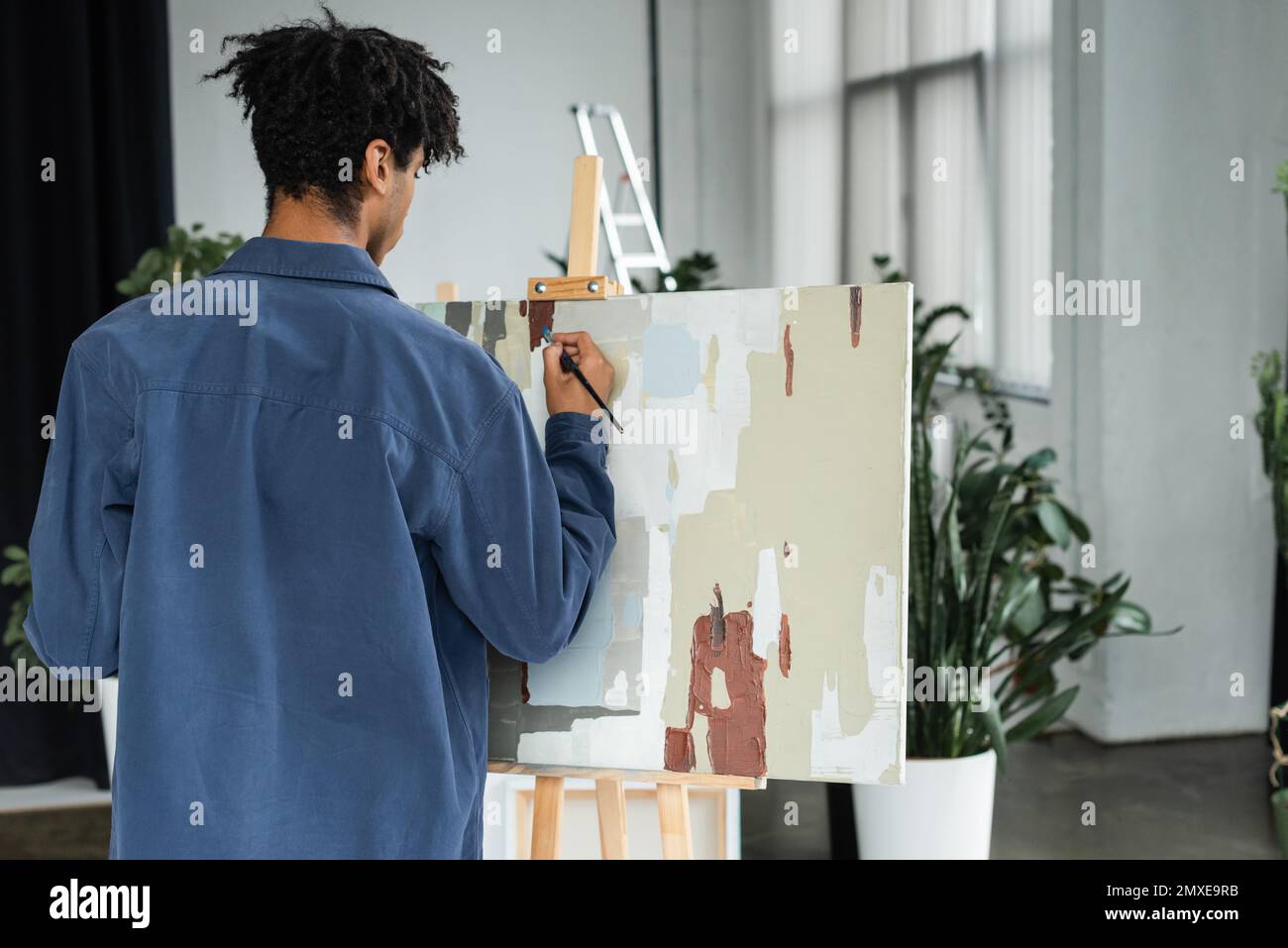Back view of african american man painting on canvas in studio,stock ...