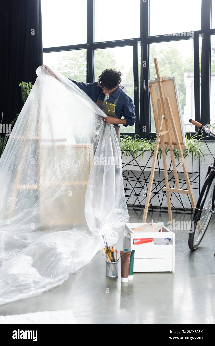 African american artist putting cellophane on easel in studio,stock ...