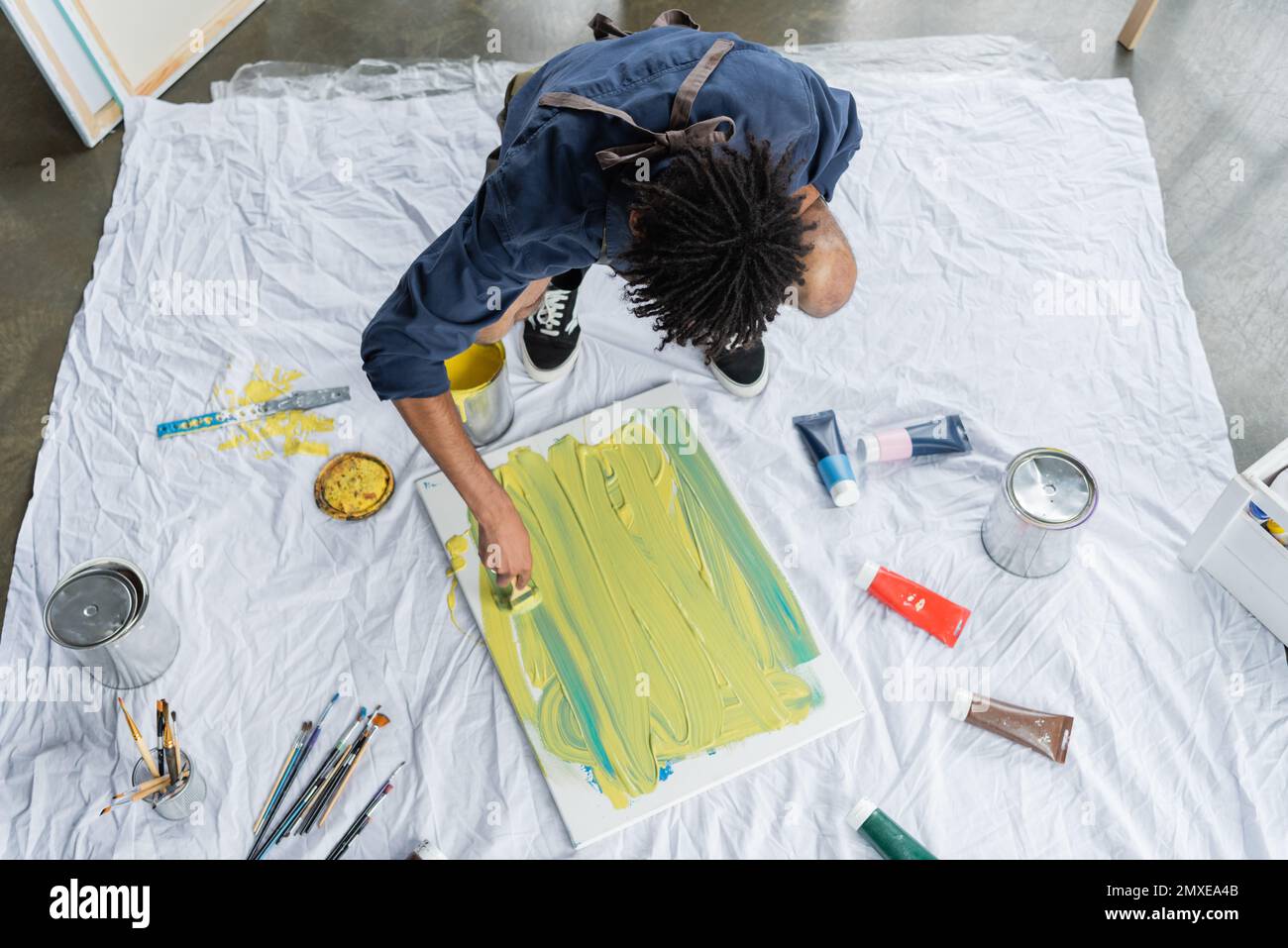 Overhead view of african american artist painting on canvas on floor ...