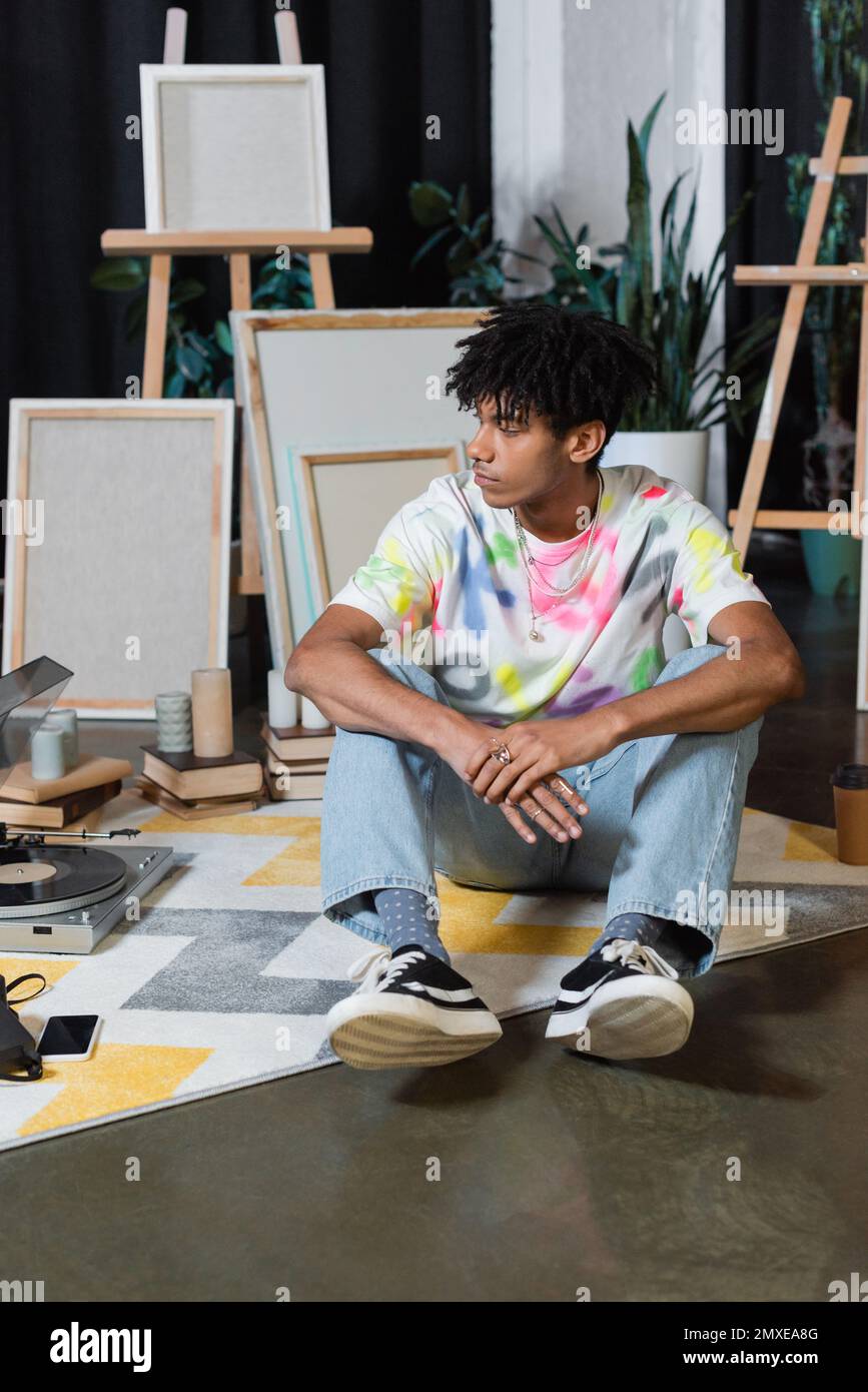 African american artist sitting near smartphone and record player in ...