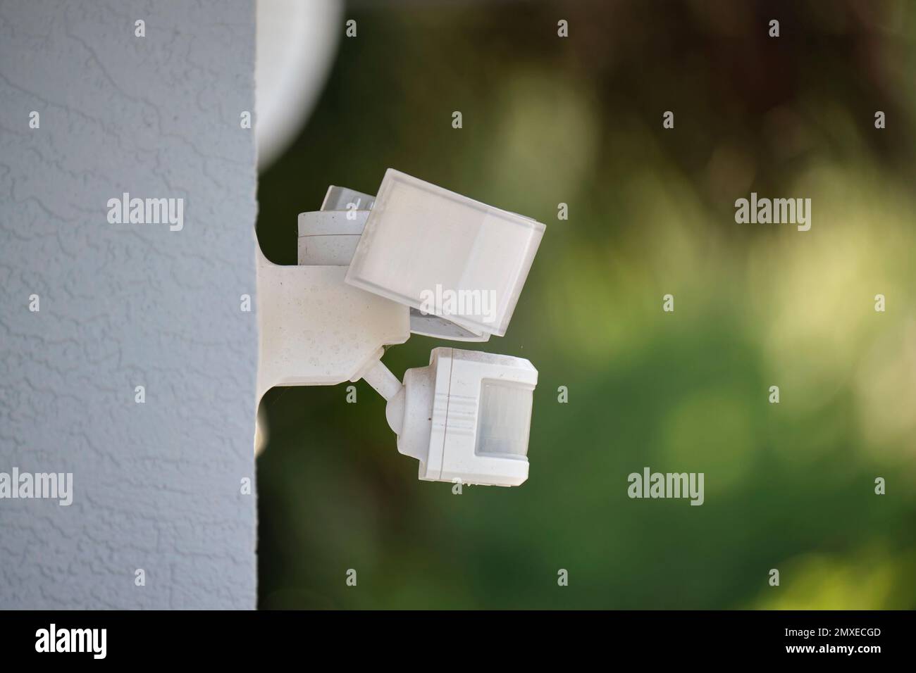 Motion sensor with light detector mounted on exterior wall of private ...