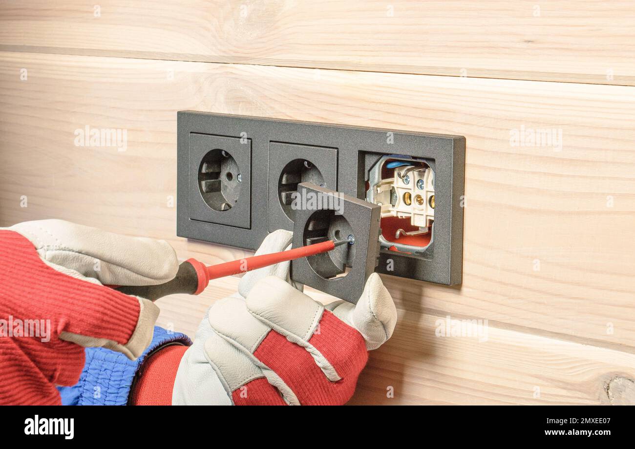 installation of a block of three black sockets on a wooden wall Stock ...