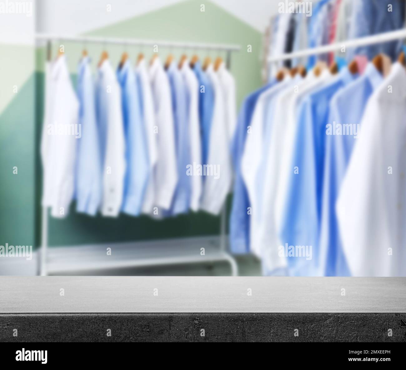 Empty grey stone surface and clean clothes on hangers in dry-cleaning ...