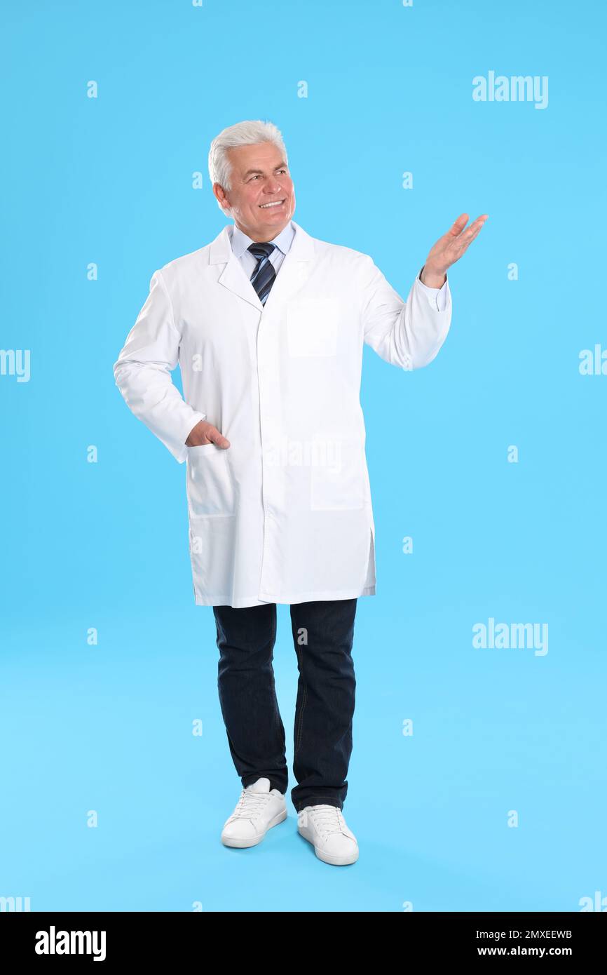 Happy senior man in lab coat on light blue background Stock Photo - Alamy