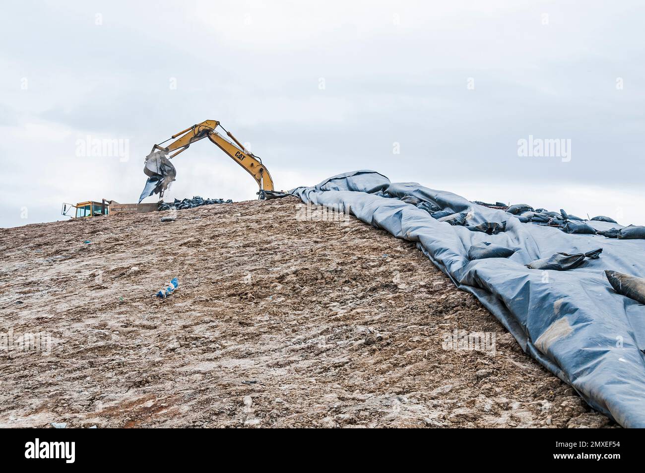 A power shovel loads debris onto a a dump truck in an active landfill ...