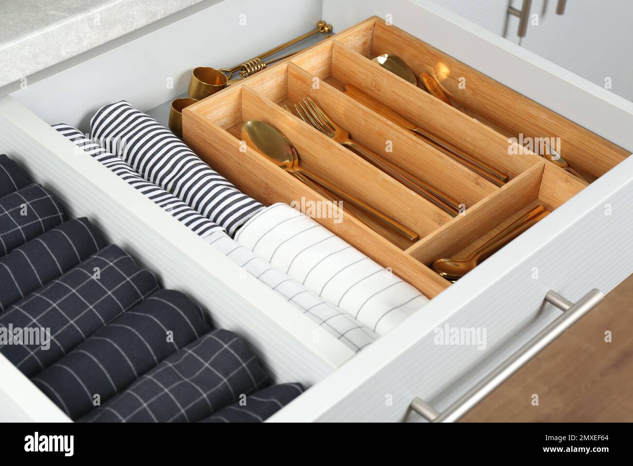 Open drawer with different utensils and folded towels. Order in kitchen ...