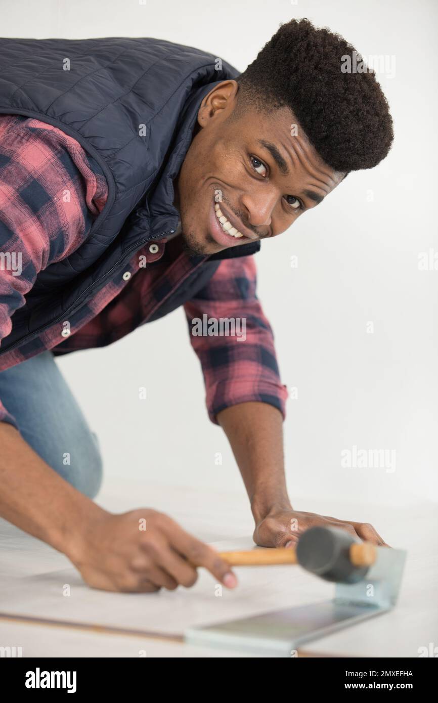 happy master picks a series of flooring with a hammer Stock Photo - Alamy
