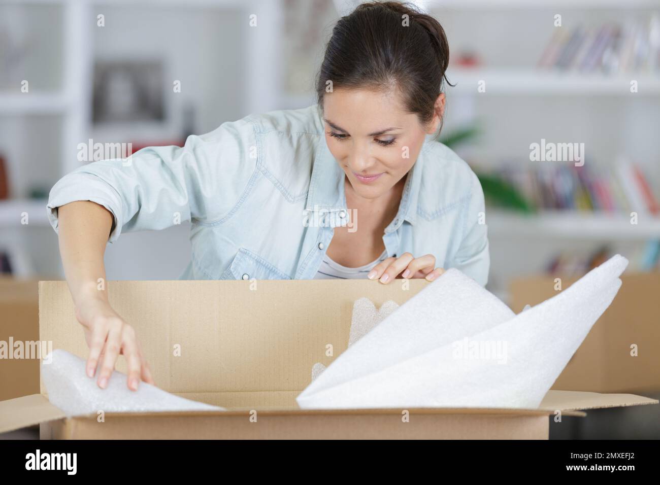 woman unpacking unboxing cardboard carton Stock Photo - Alamy