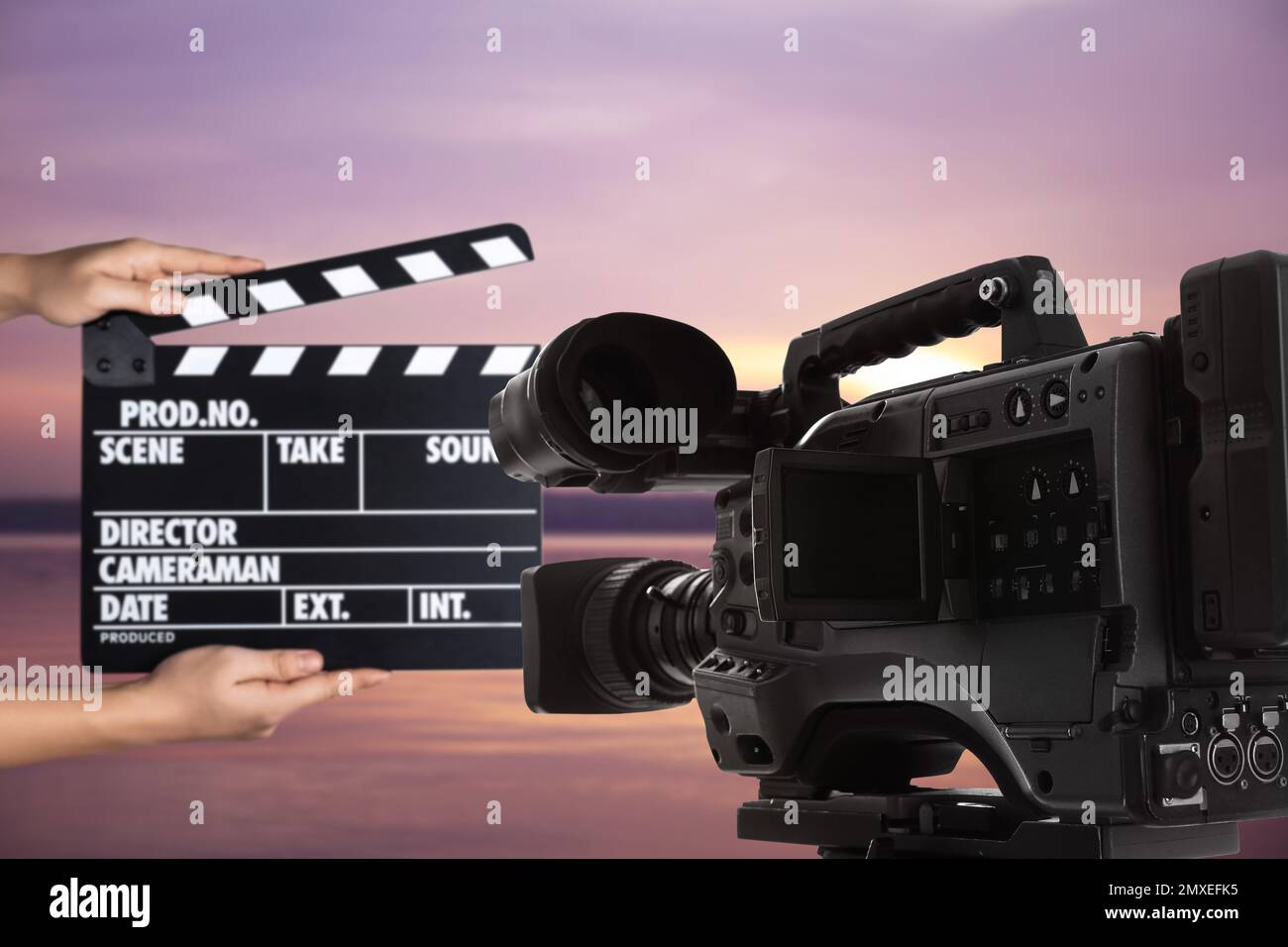 Modern video camera and assistant with clapperboard outdoors, closeup ...