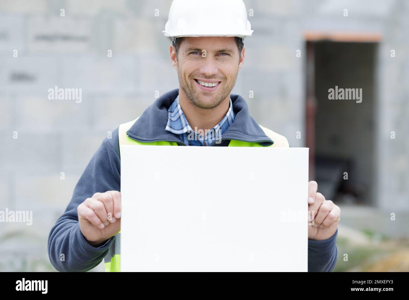 happy builder shows a white banner Stock Photo - Alamy