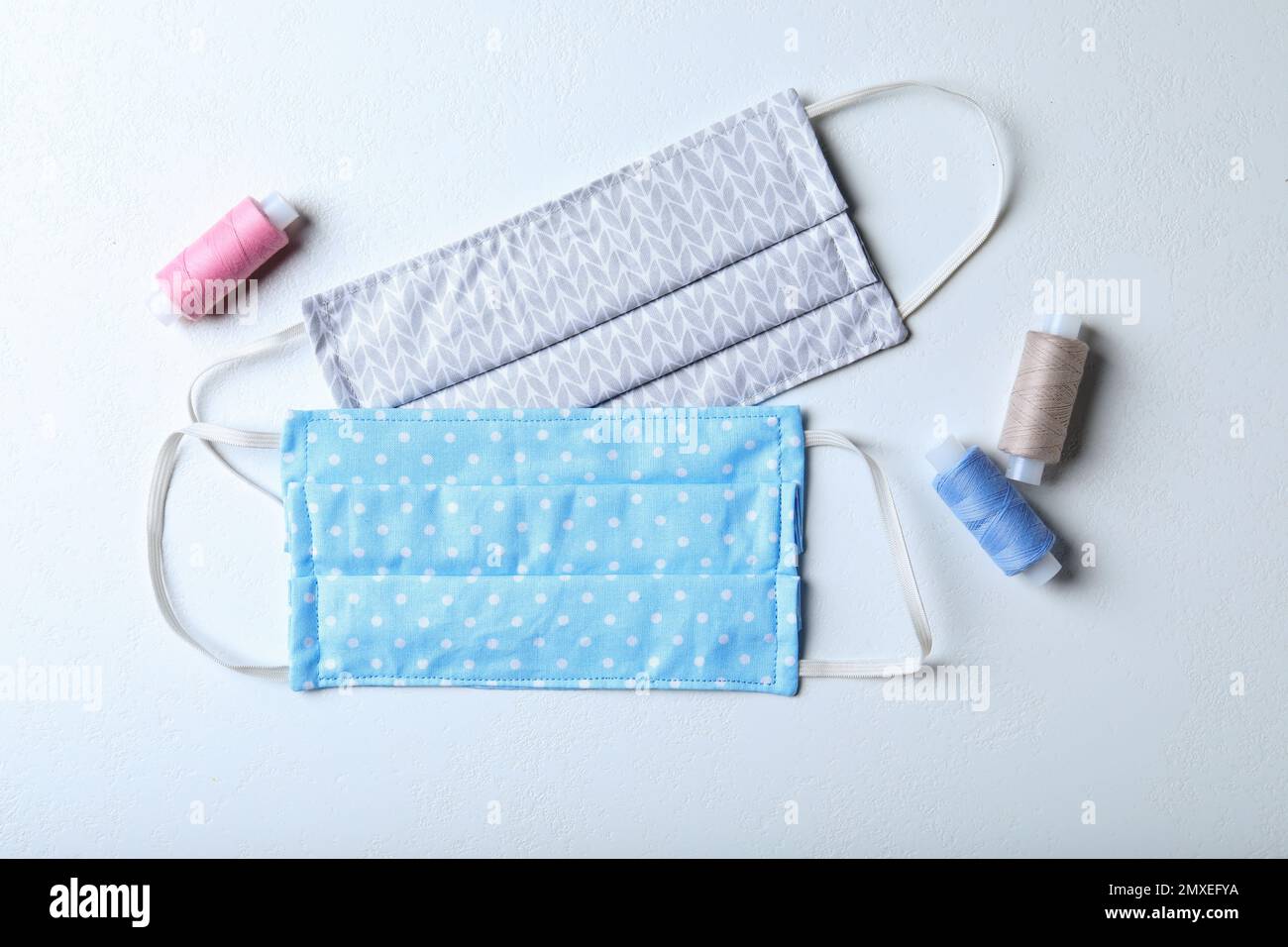 Homemade protective masks and threads on white background, flat lay ...