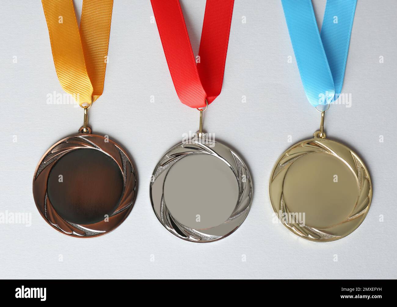 Gold, silver and bronze medals on white background, flat lay. Space for ...