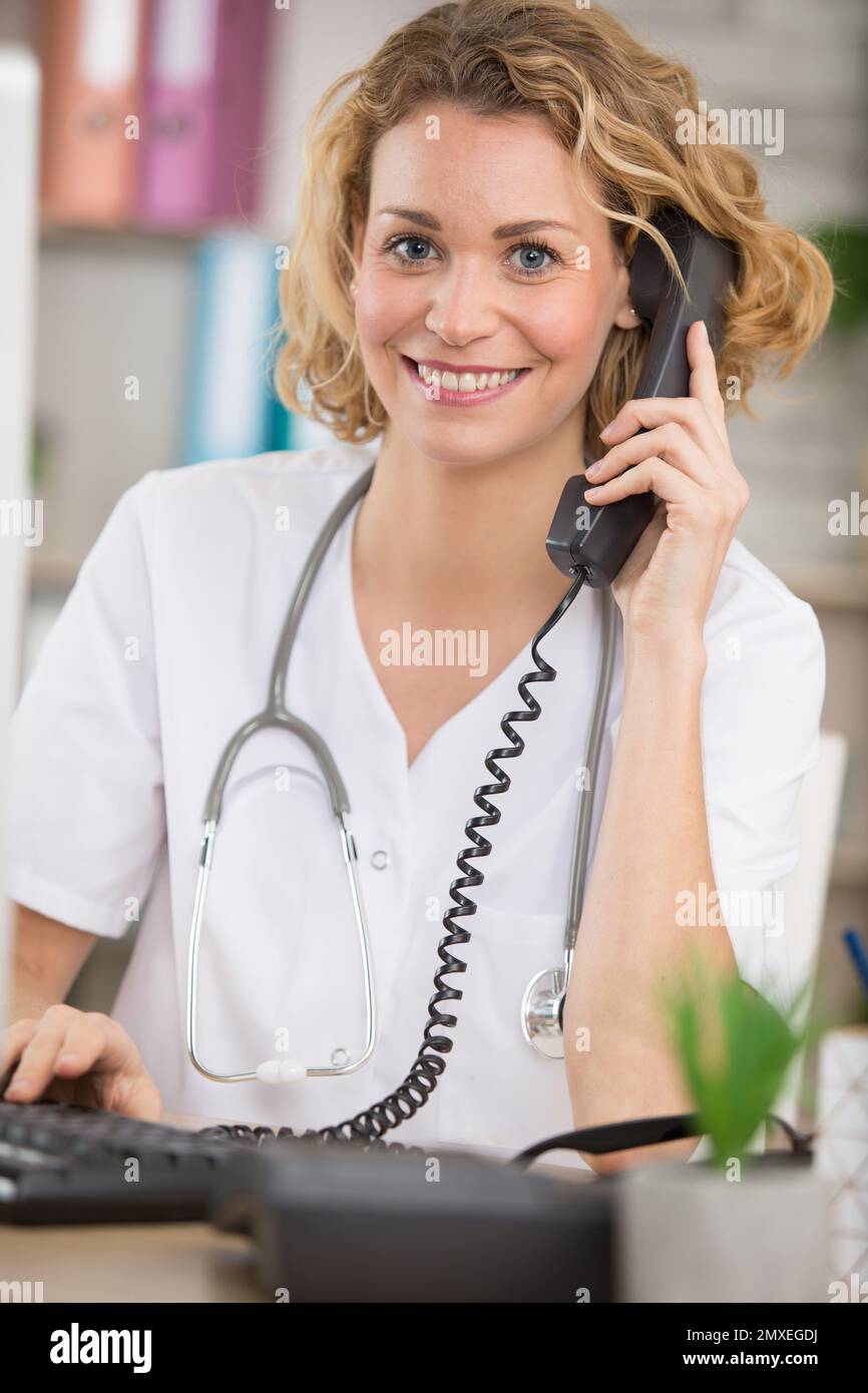 young female doctor and practitioner working at the reception desk ...