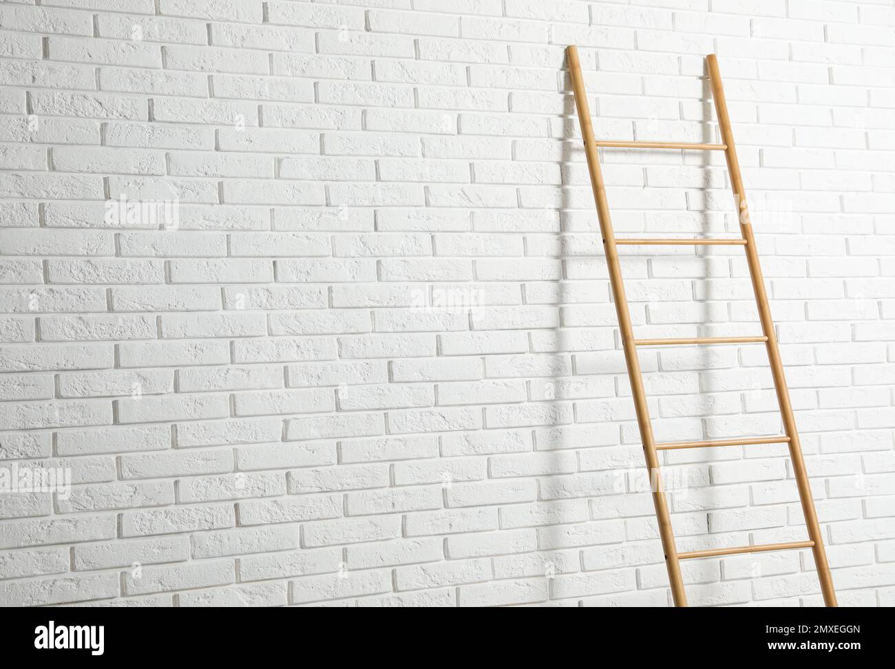 Modern wooden ladder near white brick wall. Space for text Stock Photo ...