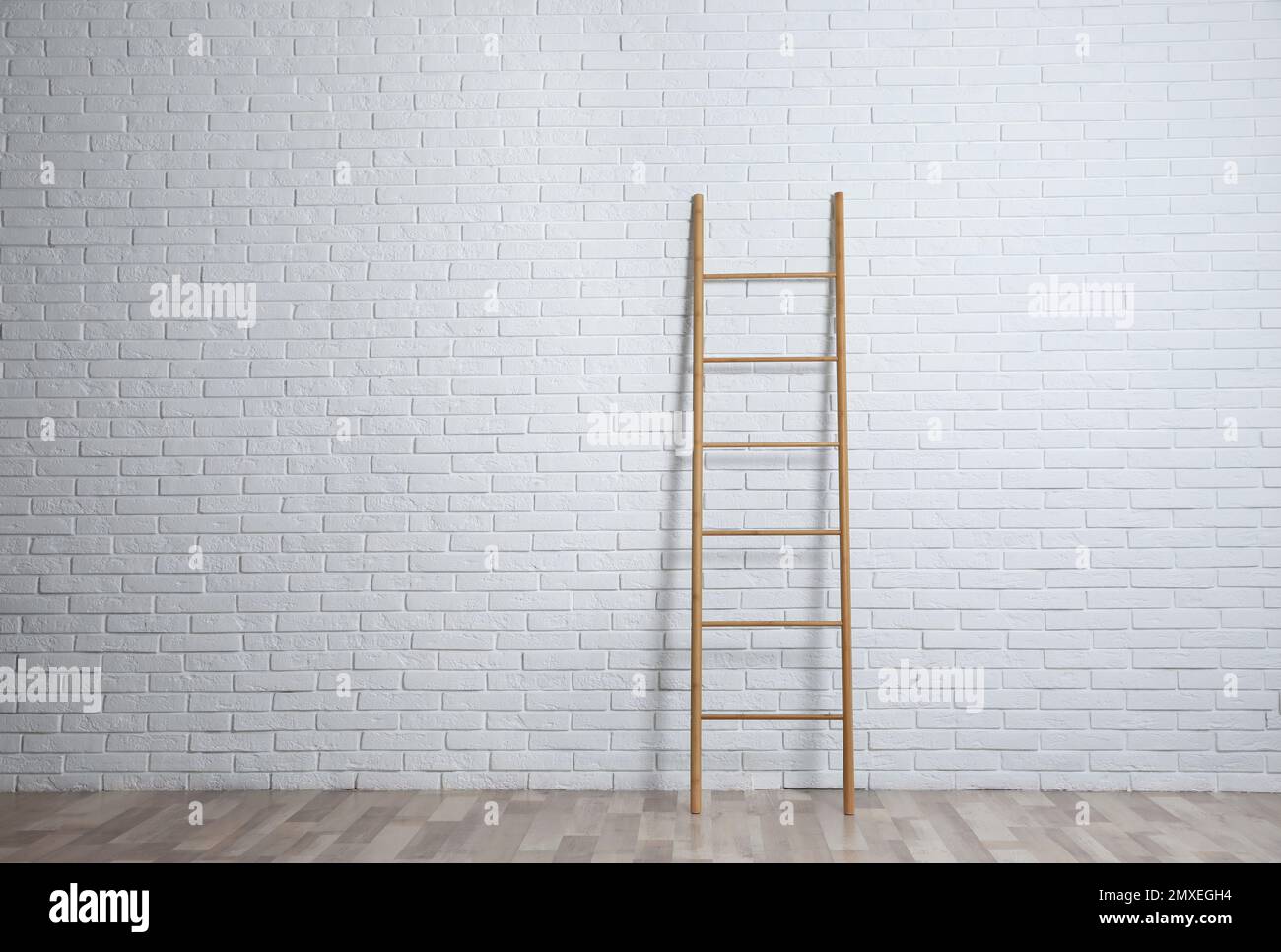 Modern wooden ladder near white brick wall Stock Photo - Alamy
