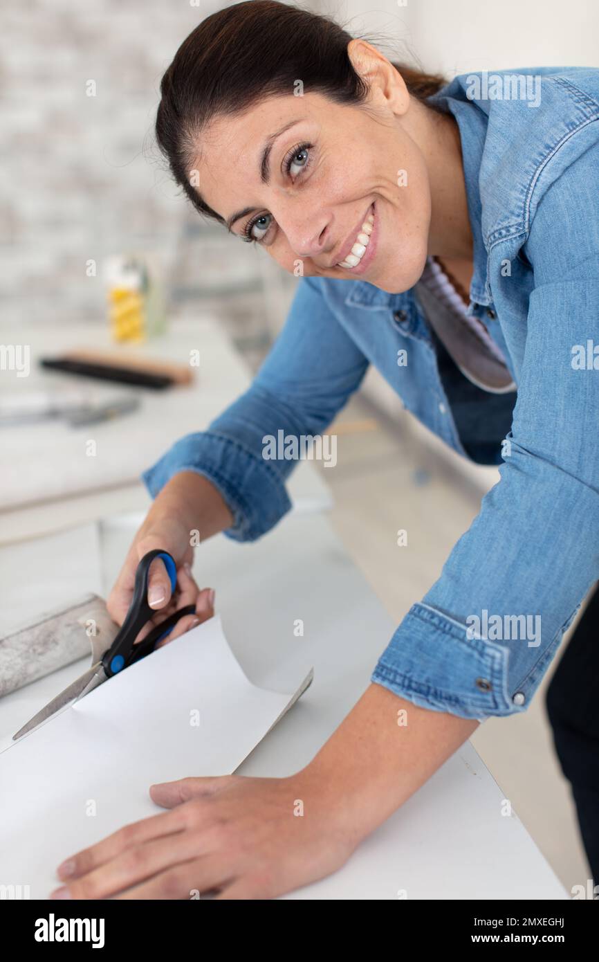a cheerul woman cutting wallpaper Stock Photo - Alamy